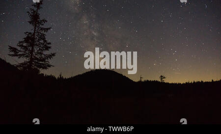 A purple starry sky over a silhouette of a mountain and a electricity ...