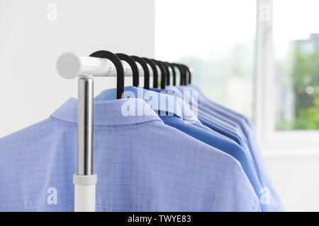 Rack with clothes after dry-cleaning on wooden background Stock Photo ...