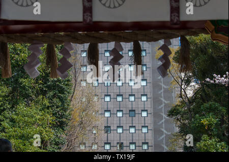 Paper Shide hang across entrance to a Shinto Shrine with view to a city ...