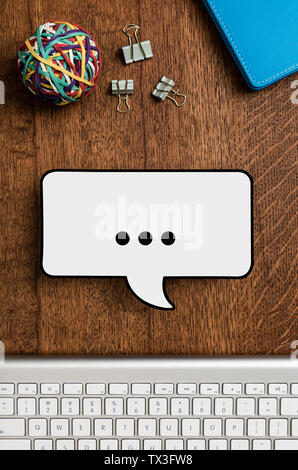 View from above paper speech bubble above computer keyboard on wooden ...