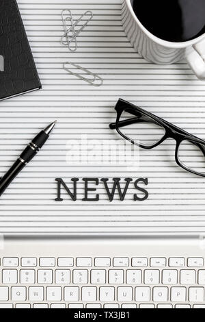Vertical shot of a cup of coffee, keyboard, and laptop on a wooden desk ...