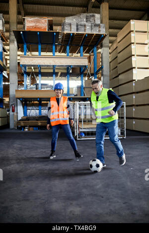 Workers playing football in factory warehouse Stock Photo - Alamy