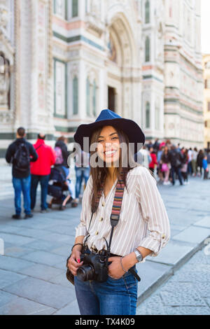 Italy, Florence, portrait of happy young tourist with camera and ...
