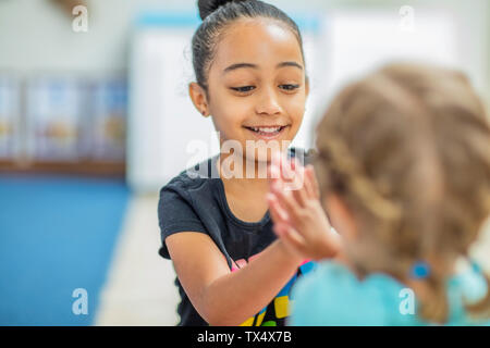 Two girls clapping hands, smiling, side view Stock Photo - Alamy