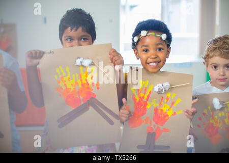 Portrait of smiling children presenting images of fire in kindergarten ...