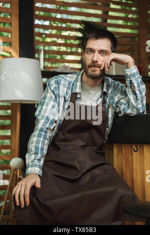 Image of handsome barista man wearing apron making coffee while working ...