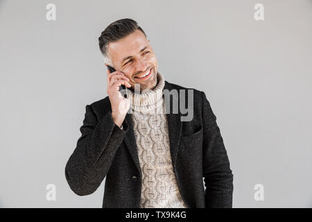 Attractive excited man wearing coat standing isolated over gray ...