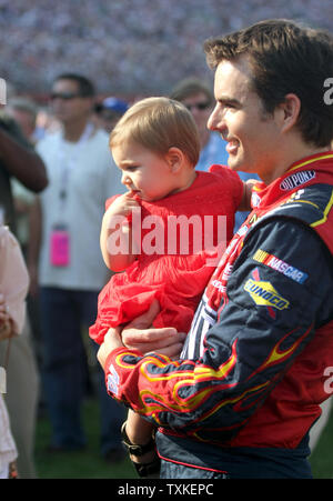 Jeff Gordon holds his daughter Ella Sophia as she tries on his racing ...