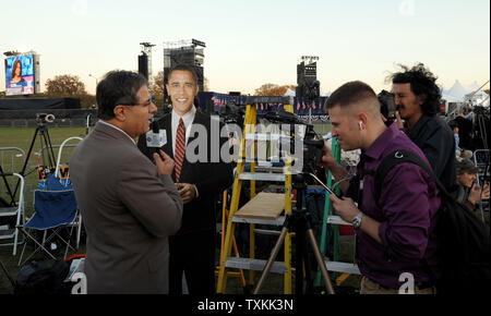 A video reporter films a report next to a cardboard cutout of ...