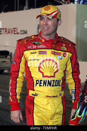 Kevin Harvick walks down pit road under an umbrella during a rain delay ...