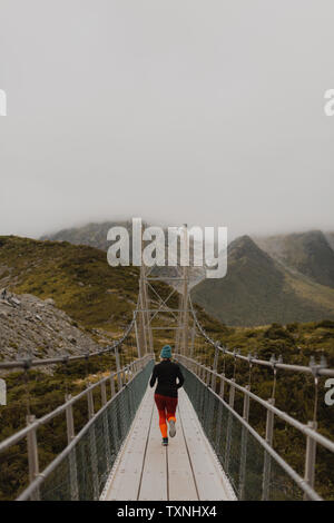 Hiker crossing suspension bridge, Wanaka, Taranaki, New Zealand Stock ...