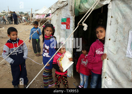 Palestinian children peer from a tent serving as temporary shelter ...