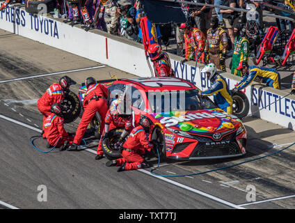 Kyle Busch's pit crew work on removing a blown tire during a pit stop ...