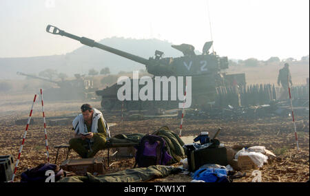 An Israeli soldier prays in the morning near a cannon in an artillery ...
