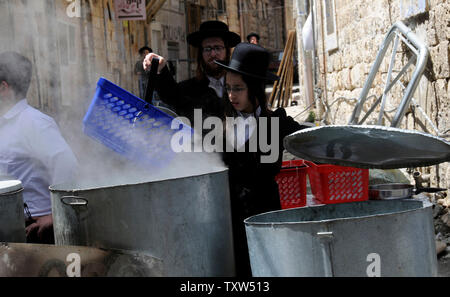 An Ultra-Orthodox Israeli dips cooking utensils into boiling water to ...