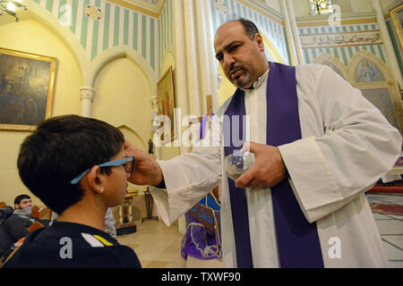 A Catholic priest places ashes on the head of a boy during mass on Ash ...