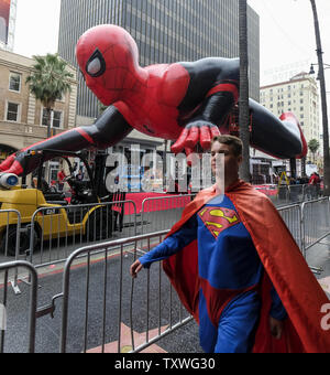A man wearing a Spider-Man costume walks past a graffiti on a wall ...