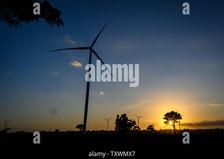 Residents walk past the turbines on Tolo 1Jeneponto wind energy power ...