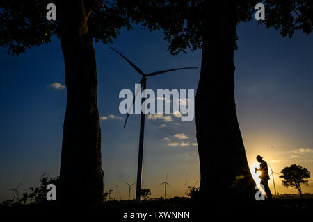 Residents walk past the turbines on Tolo 1Jeneponto wind energy power ...