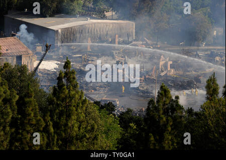 Firefighters on aerial ladders spray water on a fire as it rages out of ...