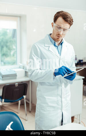 Bearded man in labcoat standing thoughtfully in a modern laboratory ...