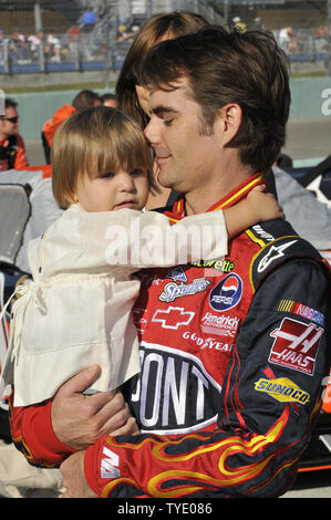 Jeff Gordon holds his daughter Ella Sophia as she tries on his racing ...