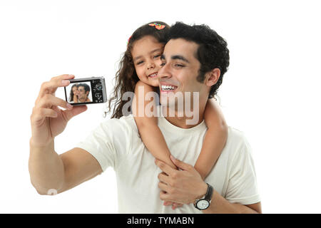 Man with her daughter taking picture of themselves with a digital ...