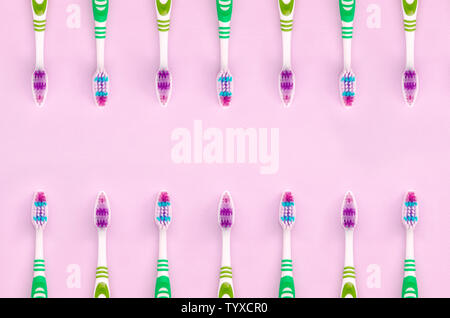 A lot of toothbrushes lie on a pastel pink background. Top view, flat ...