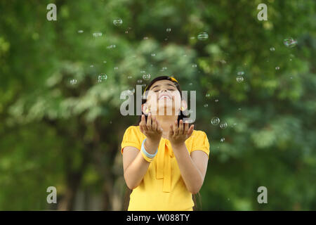 Girl trying to hold floating bubbles Stock Photo - Alamy