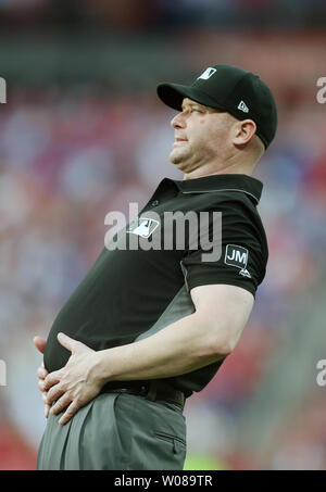 First base umpire Mike Estabrook stretches his foot between innings of ...