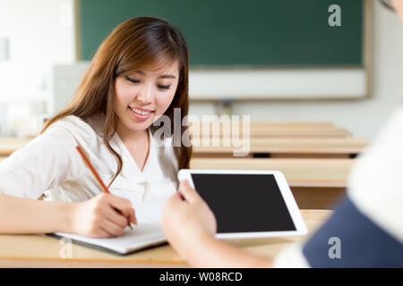 Two asian student discuss content on tablet when study in classroom ...