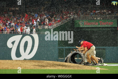 The Washington Nationals grounds crew covers the field with a tarp as ...