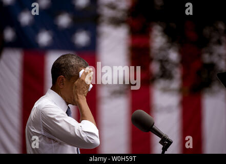 President Barack Obama wipes his face on a hot summer day as he makes a ...