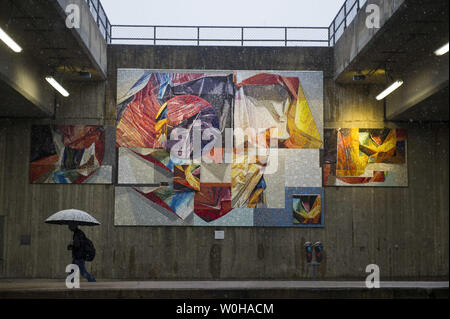 A man uses an umbrella to shield himself from the rain while walking on ...