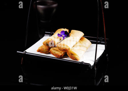 Crispy golden fried spring rolls arranged on wooden cutting board ...