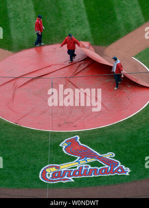 Grounds crew members remove a tarp on the field during a rain delay ...