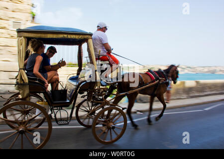 Karozzin horse drawn carriage carries tourist couple in Valletta ...