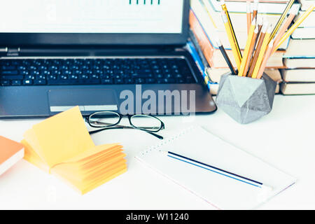 Laptop, stack of books, notebook, pencils in office background for ...