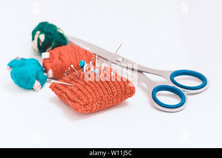 Sewing accessories. A needle pad, scissors and a spool of white thread ...