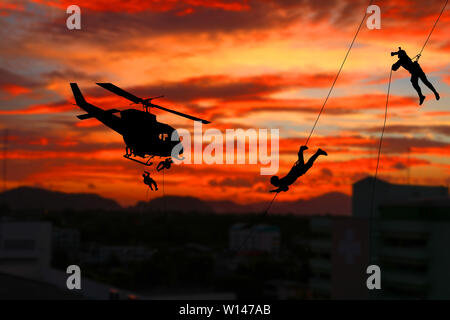 Silhouette Soldiers rappel down to attack from helicopter with sunset ...