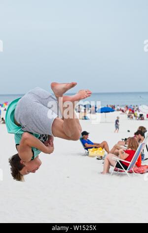 Teenage boy doing backflip on the same at the beach in Pensacola ...