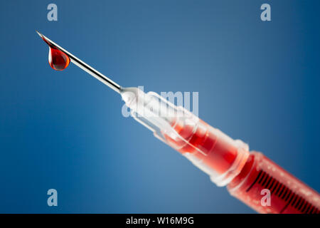 Syringe filled with blood and dripping from the needle - isolated on ...