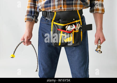 Plumber with tools belt on light background, closeup Stock Photo - Alamy