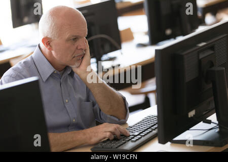 Thoughtful businessman staring at desktop monitor Stock Photo - Alamy