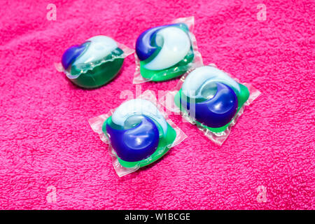 Laundry detergent and towels on table against pink background Stock ...
