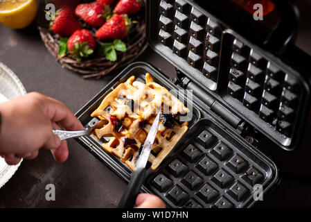 Man making waffles on a waffle machine close up Stock Photo - Alamy