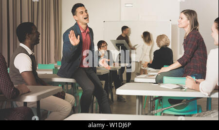 Friendly multinational group of students talking in classroom having ...