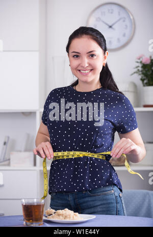 Young woman measuring a waist near the mirror Stock Photo - Alamy