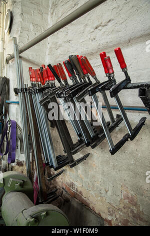 row of clamps hanging on a wall on factory floor Stock Photo - Alamy
