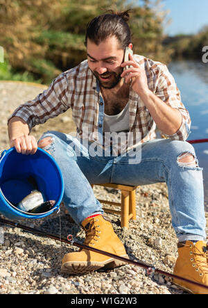 Adult fisherman talking on mobile phone by the river Stock Photo - Alamy